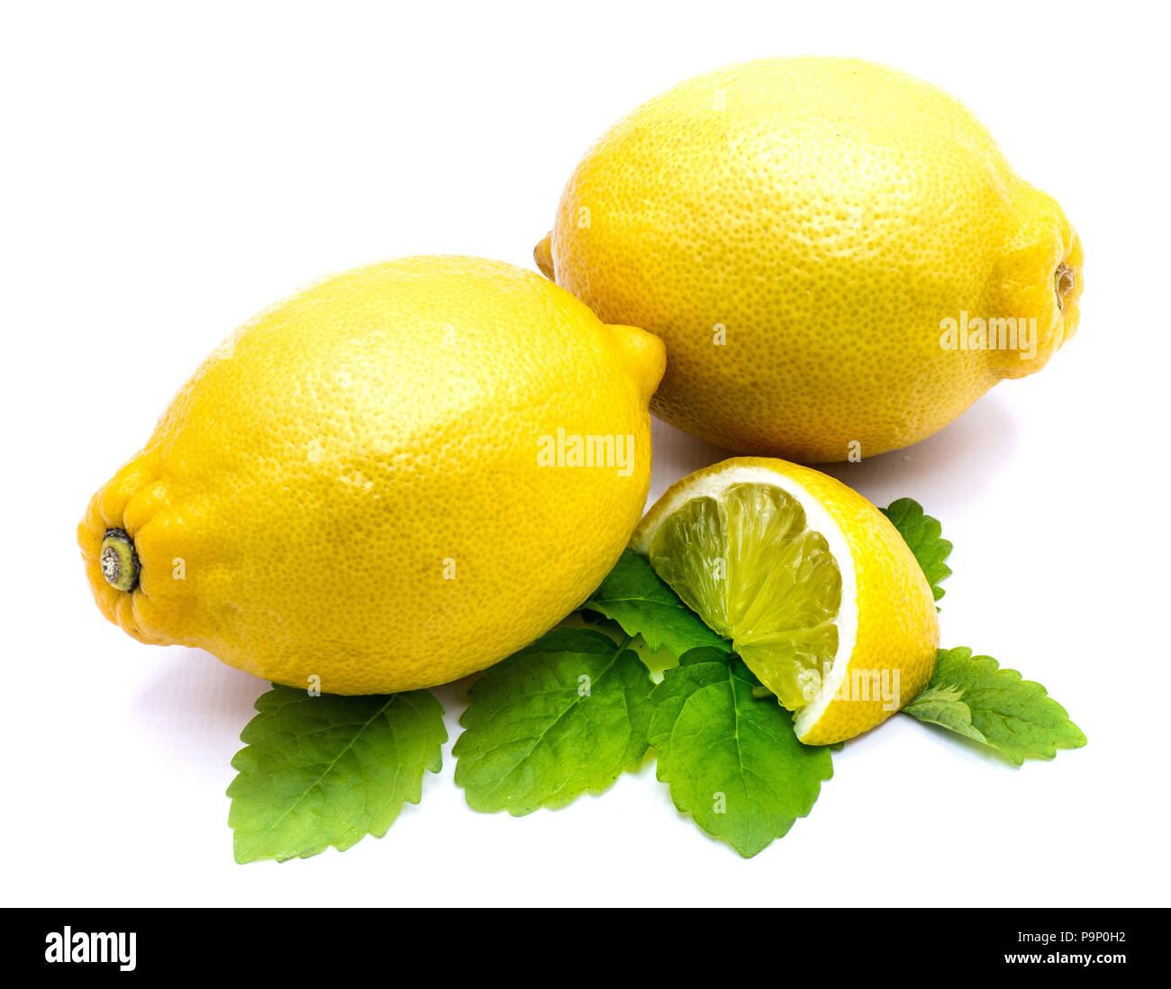 Two whole yellow lemons and slice with fresh lemon balm leaves isolated ...