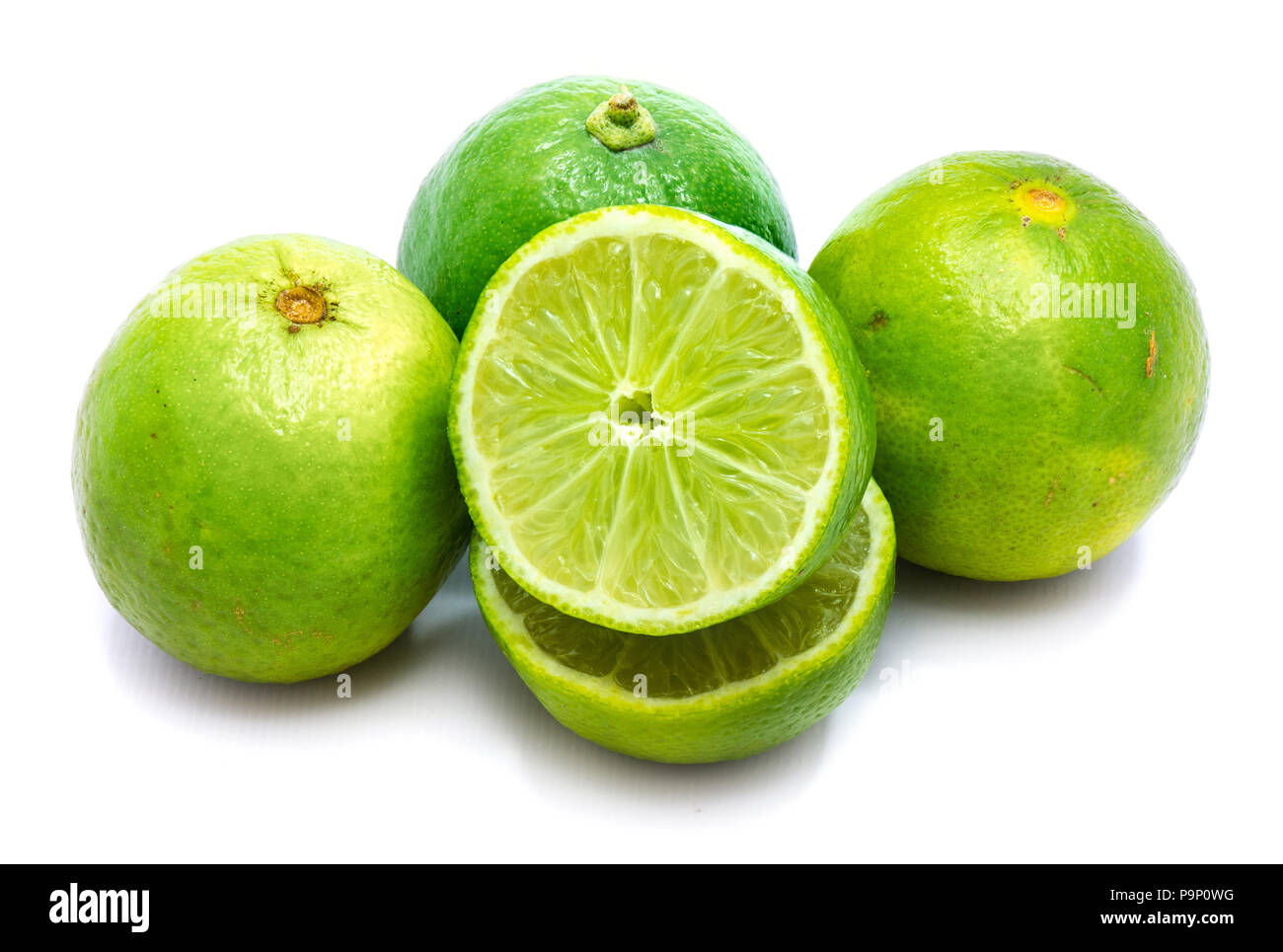 Three whole green limes and two halves isolated on white background ...