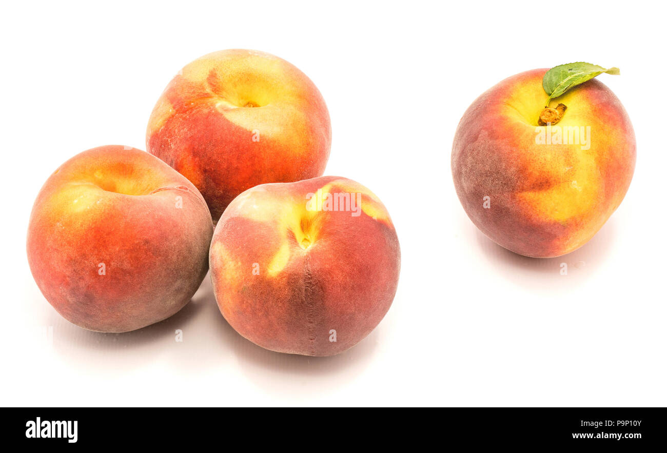 Group of four whole peaches, one with green leaf, isolated on white ...