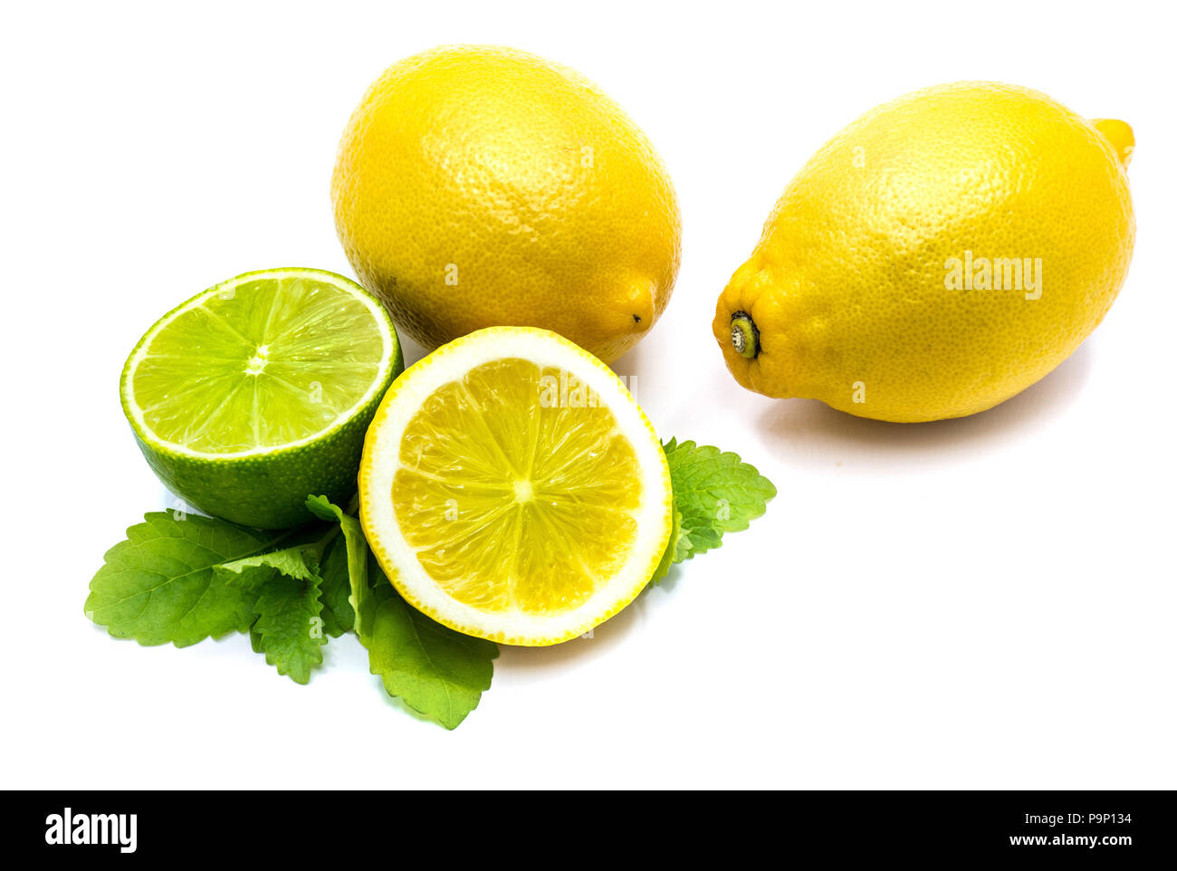 Two whole lemons, lime and lemon half with fresh lemon balm leaves ...
