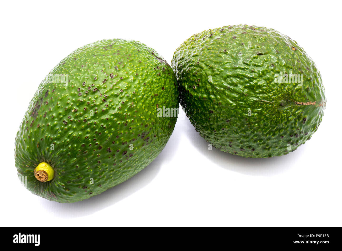 Two whole avocado (Persea americana, alligator pear) isolated on white ...