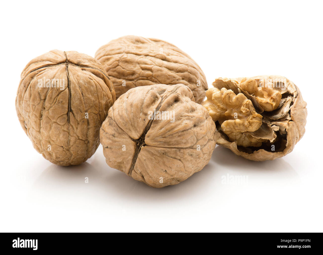 Three unshelled walnuts and broken half with nutmeat isolated on white ...