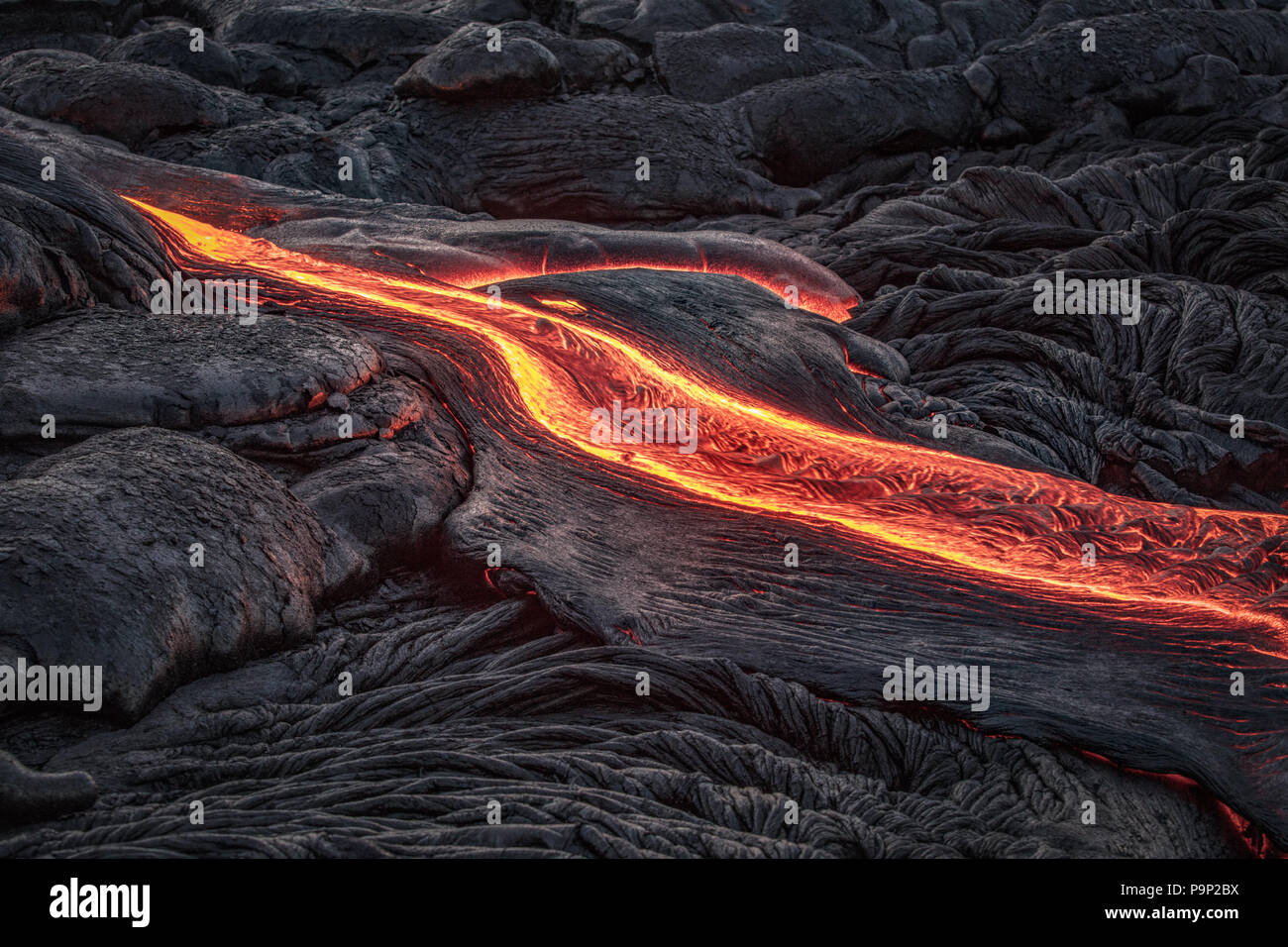 Red lava flow from black volcanic ground on melted dark background ...