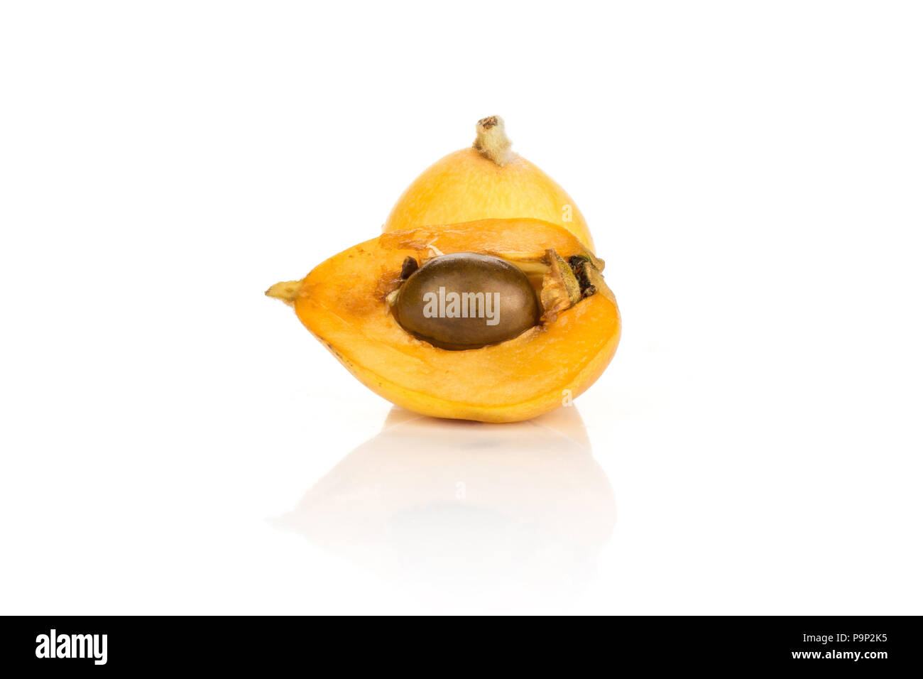 One orange Japanese loquat and section half with a seed isolated on ...