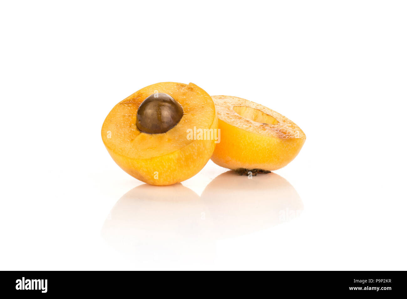 One fresh orange Japanese loquat cut in two halves with a seed inside ...