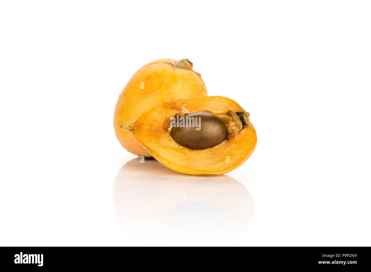 One orange Japanese loquat half with a seed and whole fruit isolated on ...