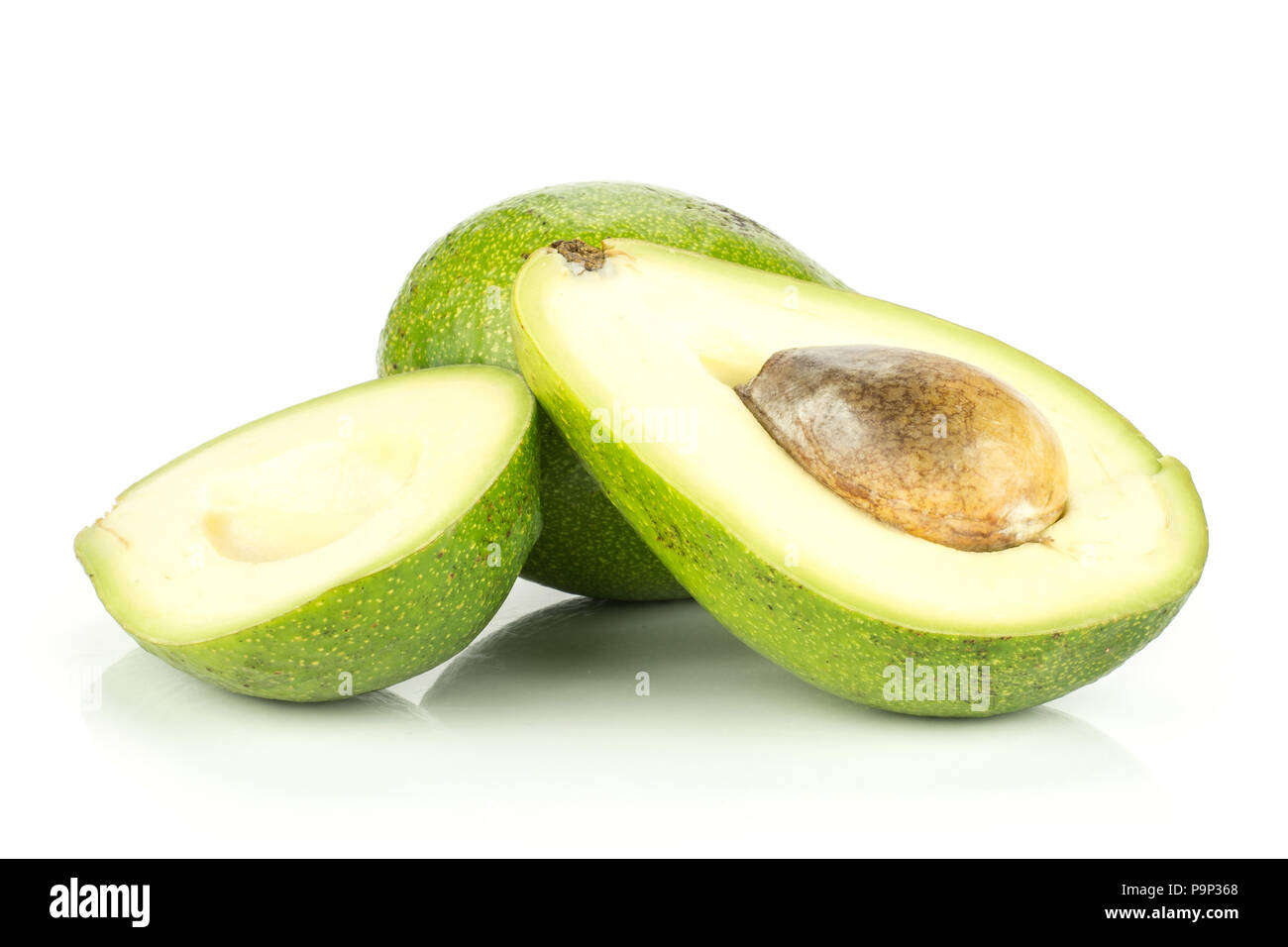 Green smooth avocado and two sliced halves with a seed isolated on ...