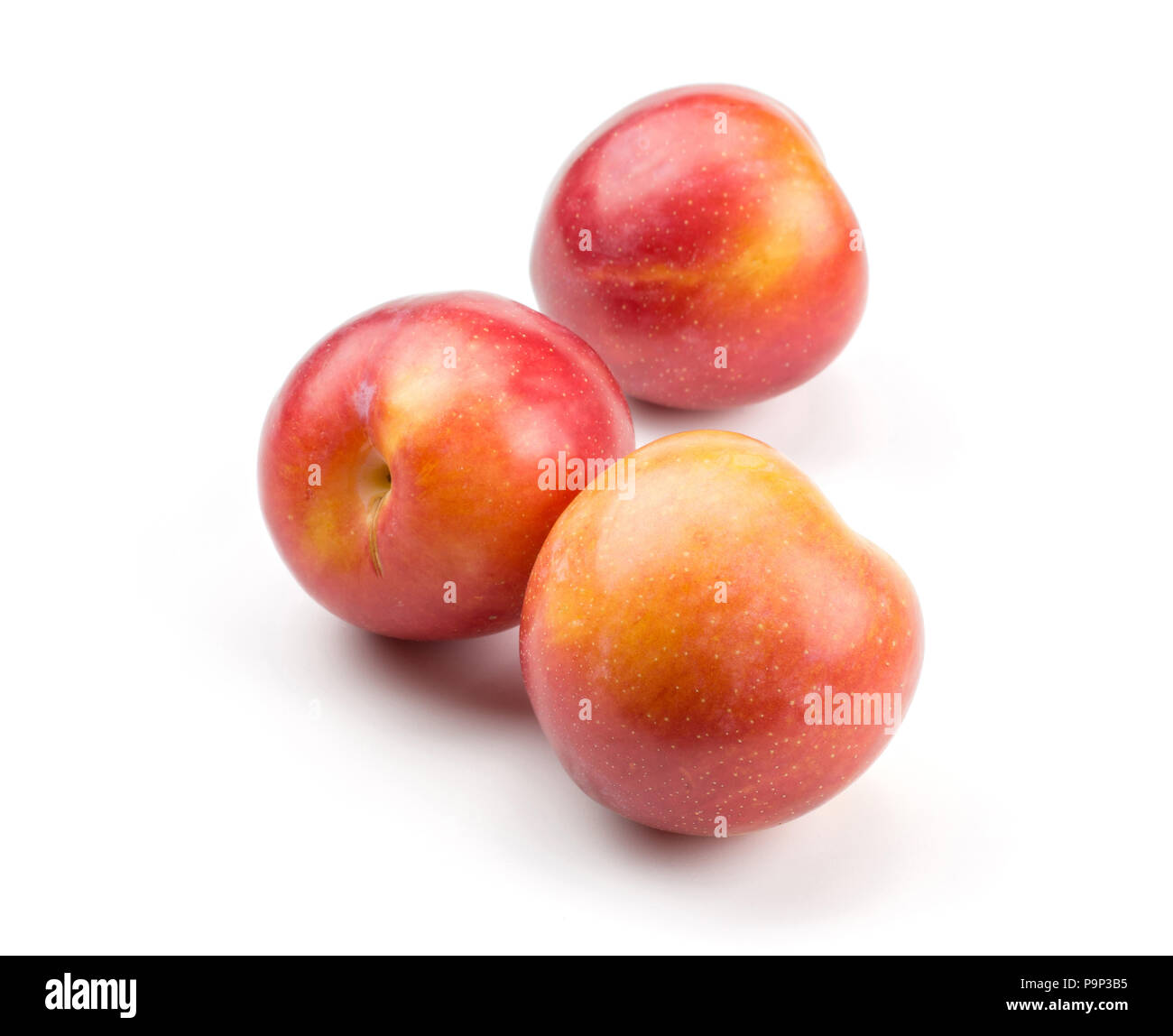 Three plums red orange isolated on white background Stock Photo - Alamy