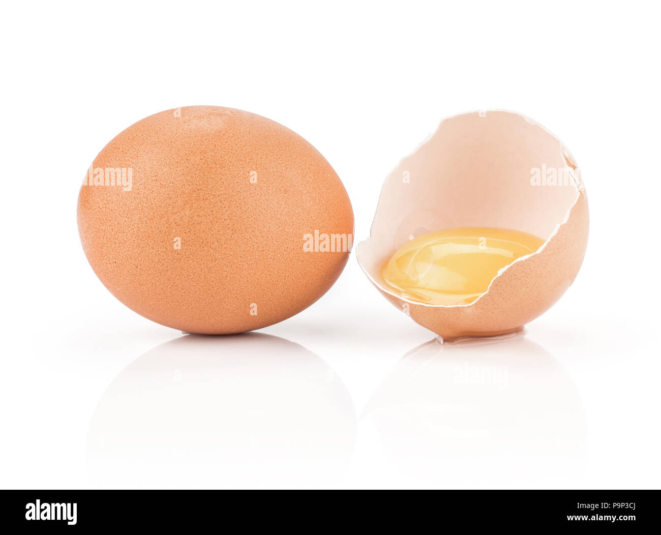 One whole brown chicken egg and one cracked half with raw yolk isolated ...
