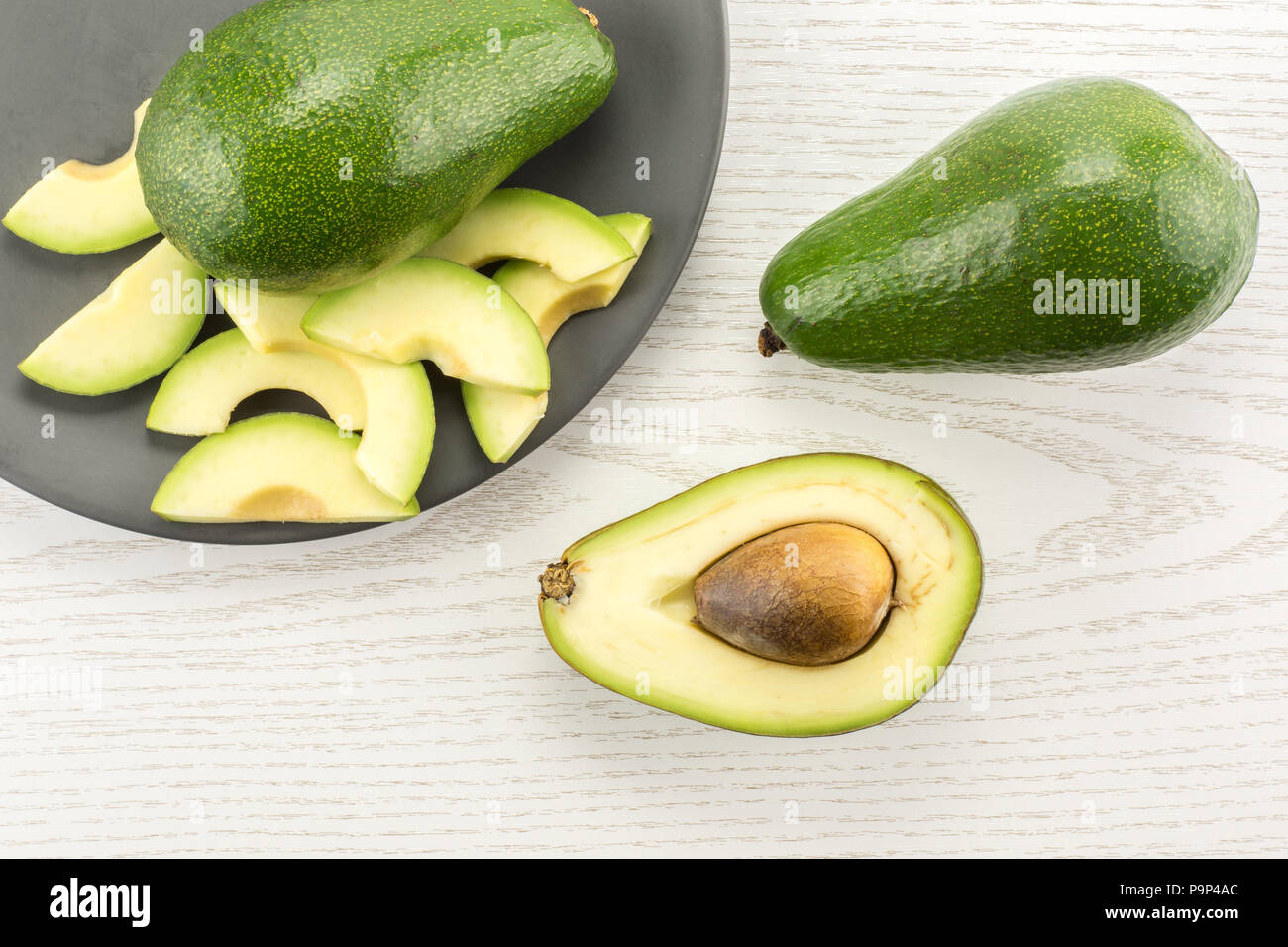 Green smooth avocado sliced composition on a grey plate table top ...