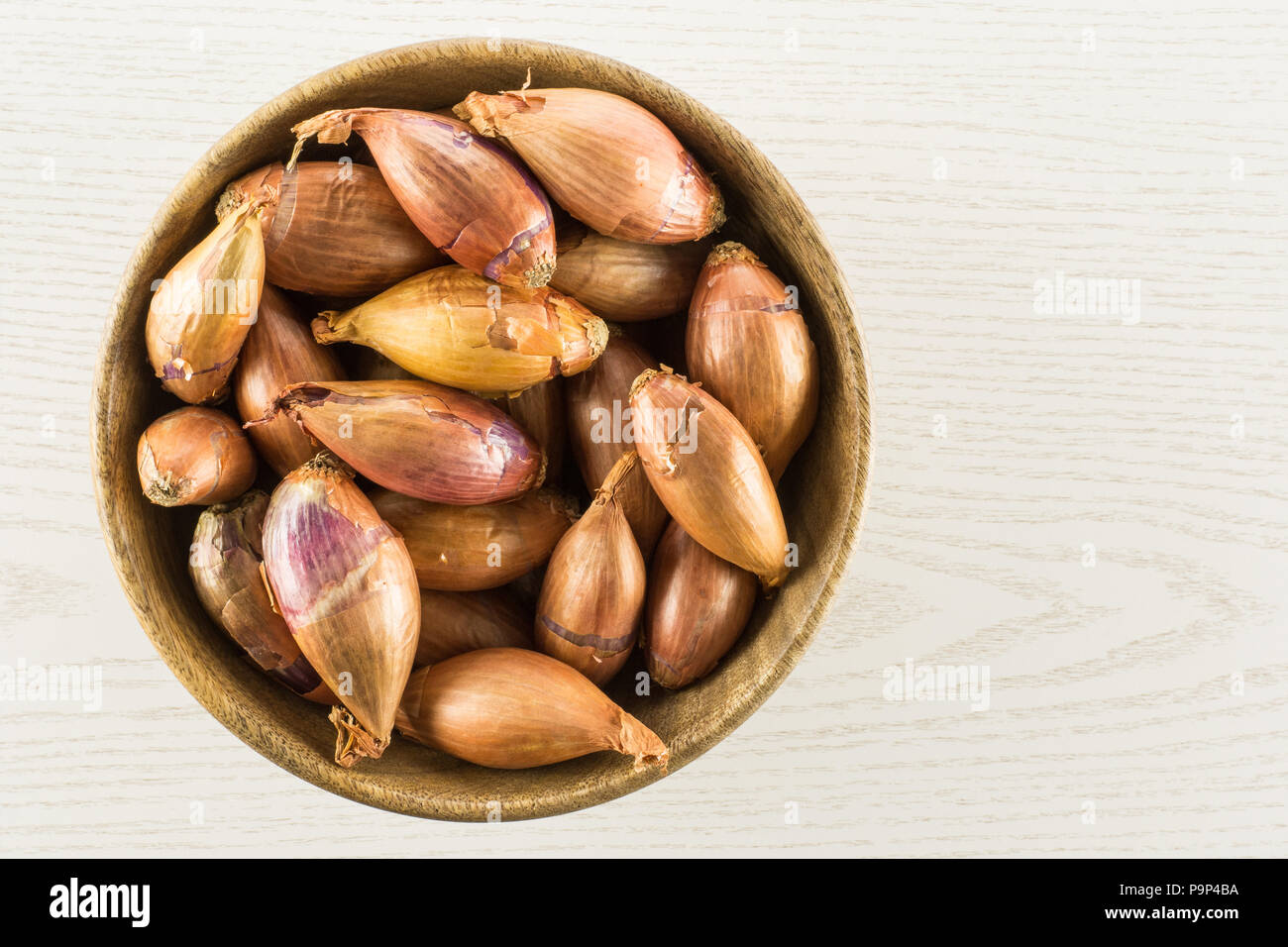 Long shallot in a wooden bowl top view isolated on grey wood background ...