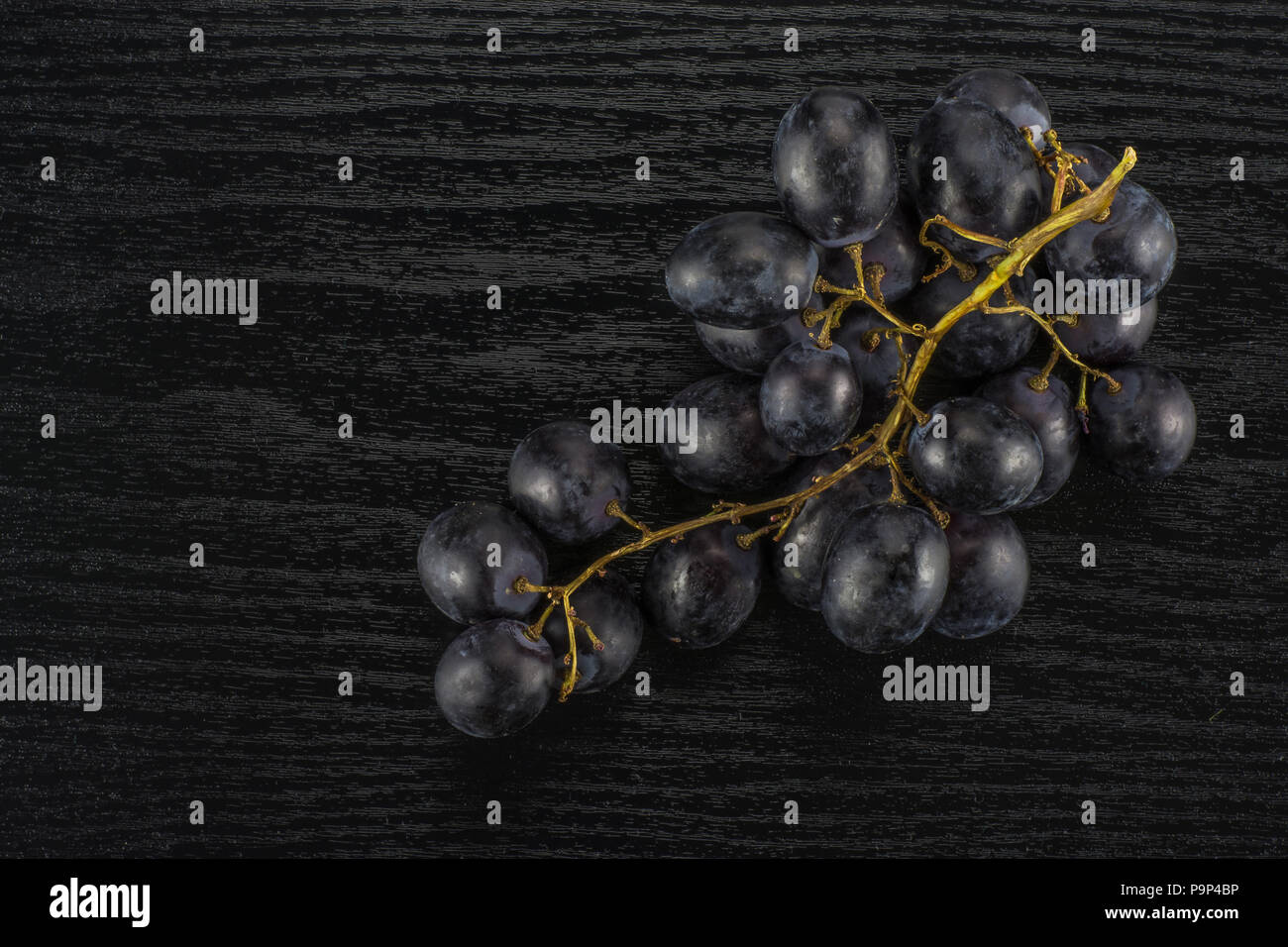 Black grape cluster (autumn royal variety) table top isolated on black ...
