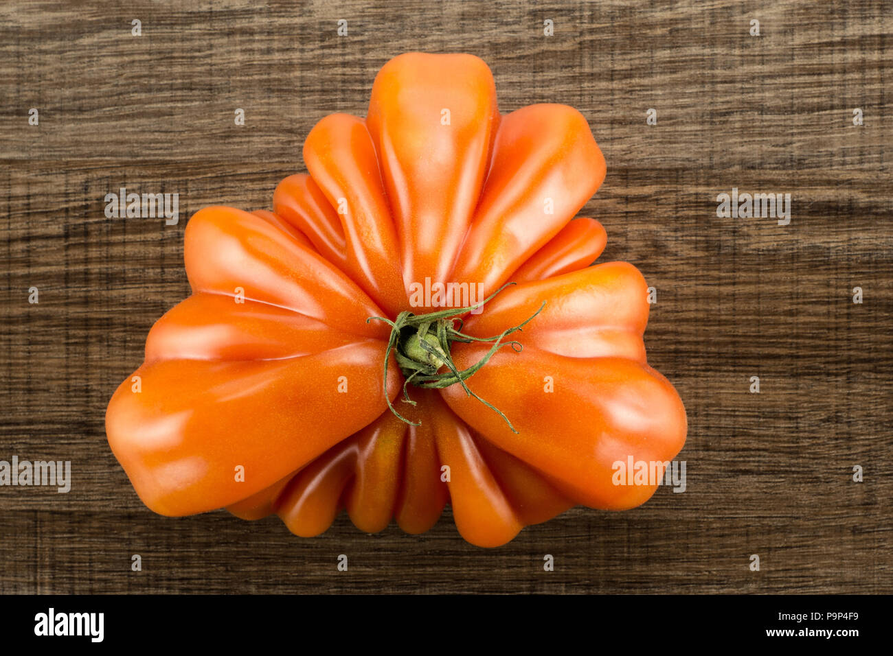 Beef tomato (triangle shape) top view isolated on brown wood background ...