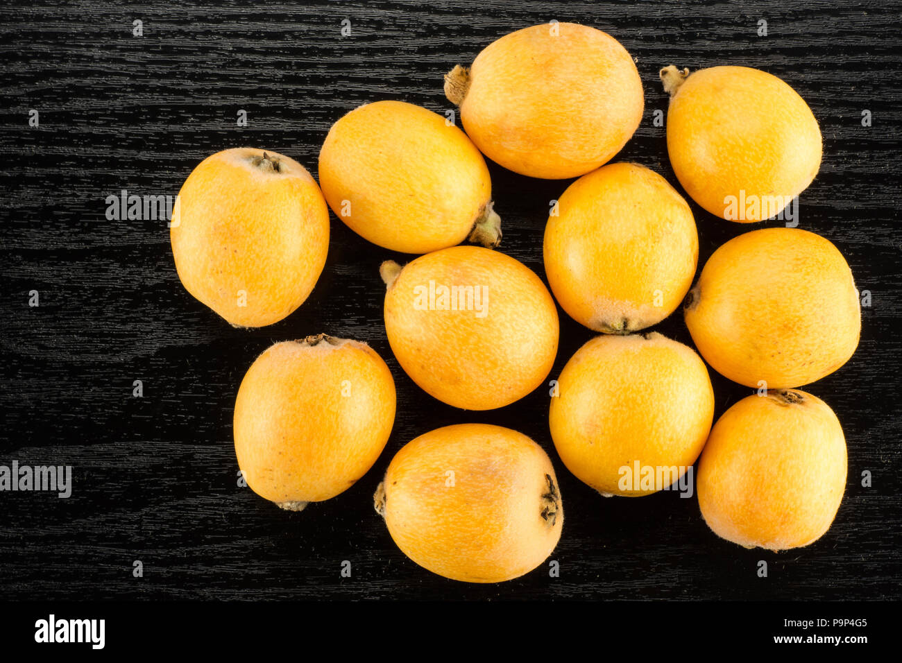Fresh orange Japanese loquats top view isolated on black wood ...