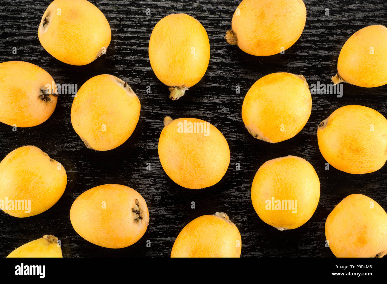 Fresh orange Japanese loquats flatlay isolated on black wood background ...