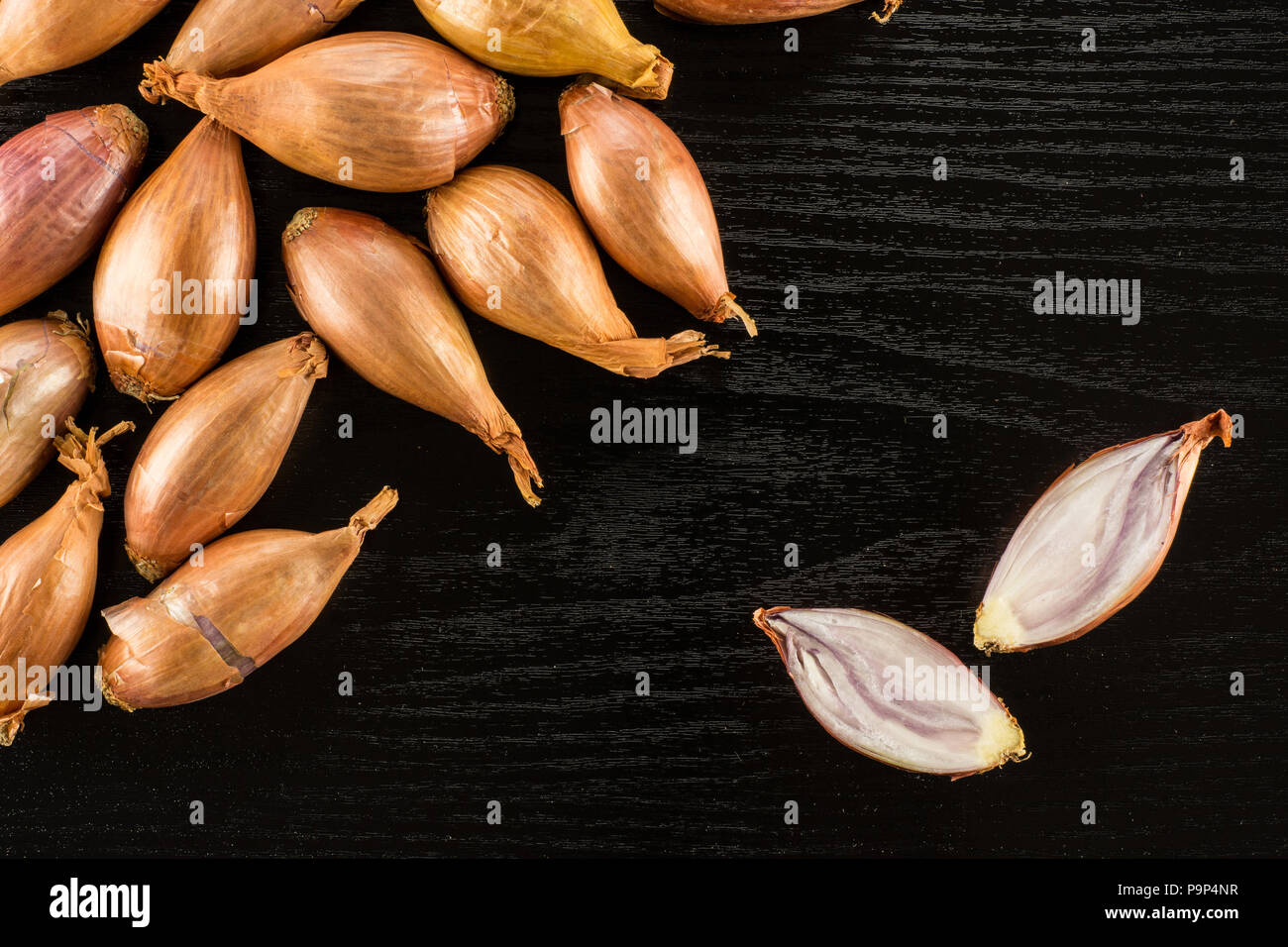 Long golden shallots one cut in two halves flatlay isolated on black ...