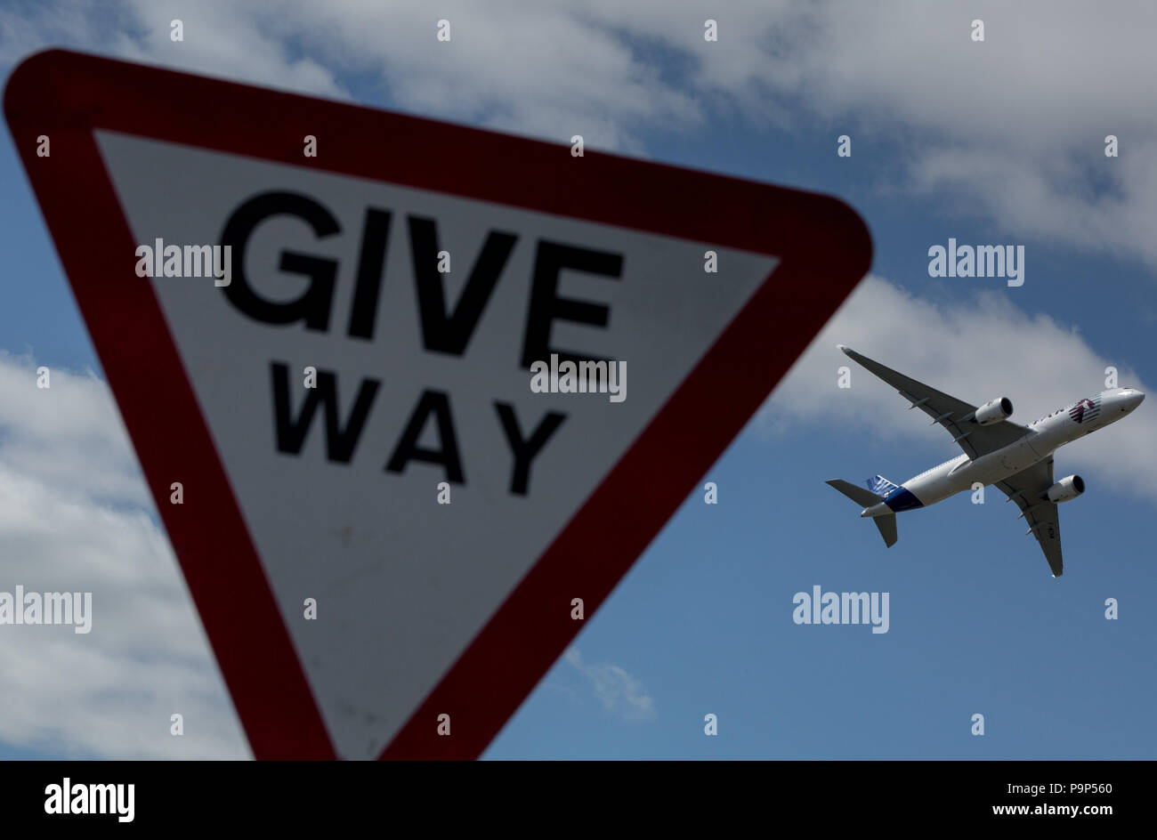 The Airbus A350 civil jet aircraft flies over the 'Give Way' sign at ...