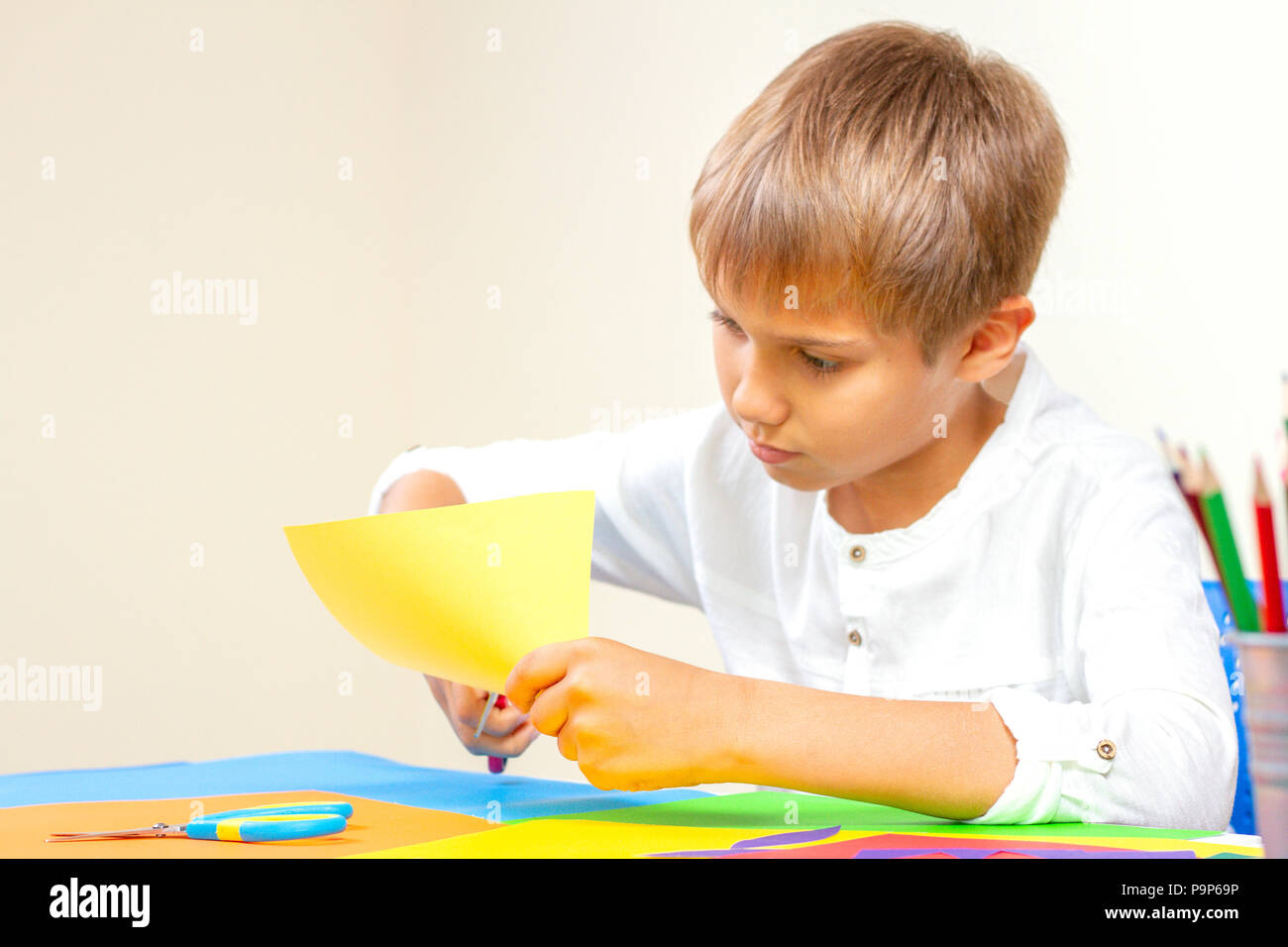 Child cutting colored paper with scissors at the table Stock Photo - Alamy