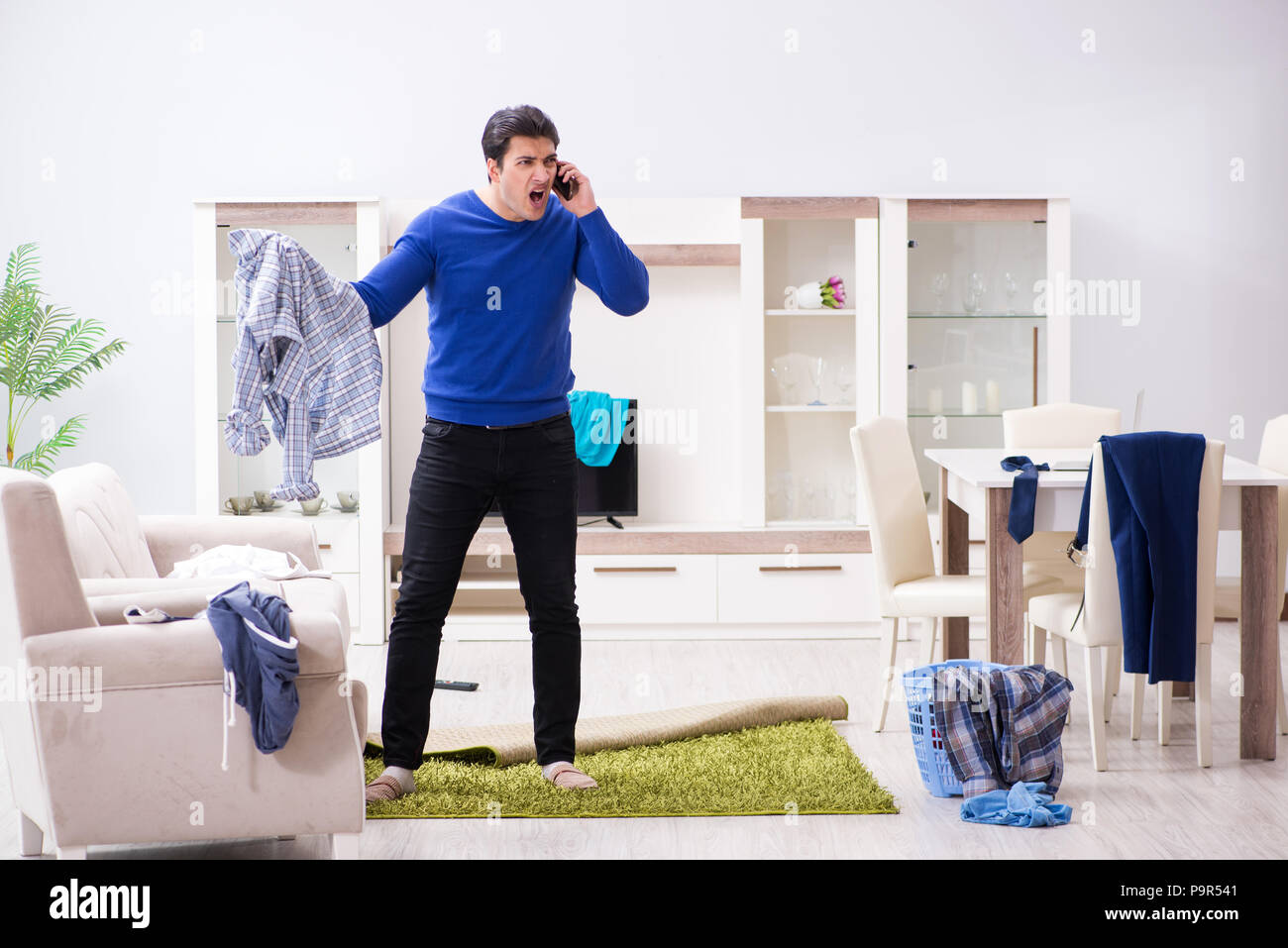 Young man collecting dirty clothing for laundry Stock Photo - Alamy