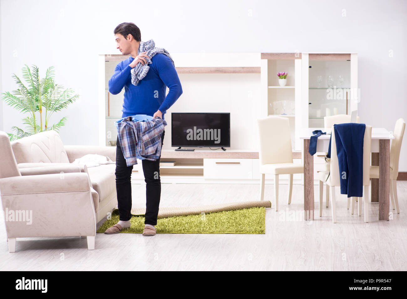 Young man collecting dirty clothing for laundry Stock Photo - Alamy