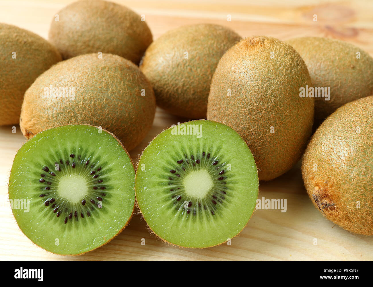 Heap of whole fruits and cross-sections of fresh kiwi fruits on the ...