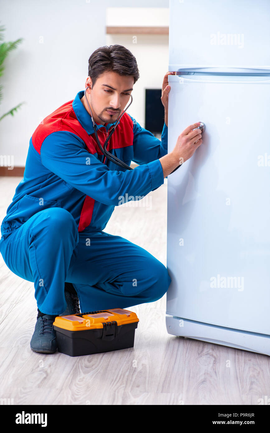 Professional contractor repairing broken fridge Stock Photo - Alamy