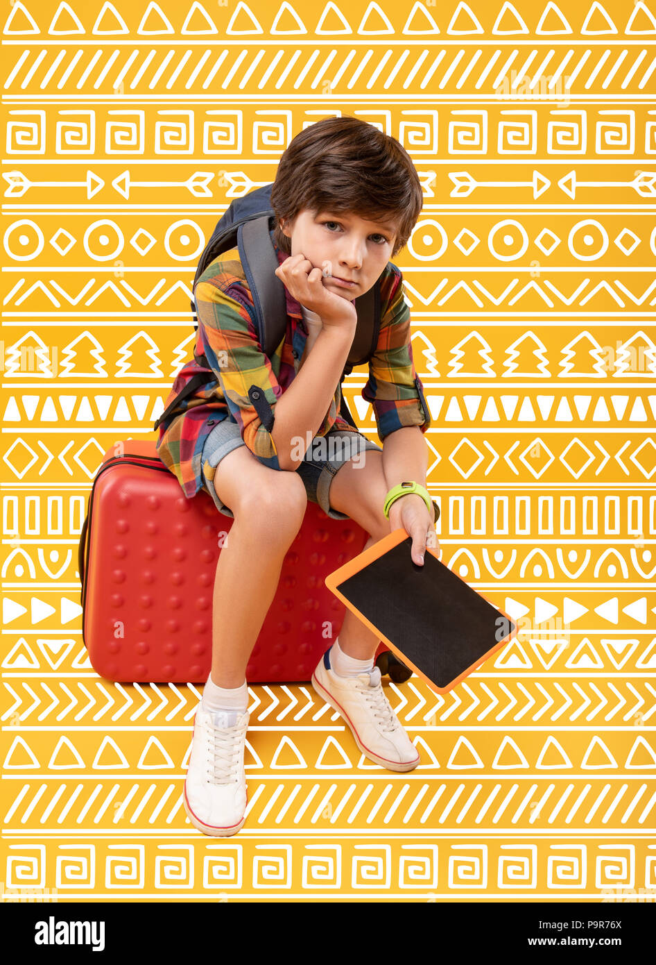 Gloomy child feeling tired while sitting on the luggage Stock Photo - Alamy