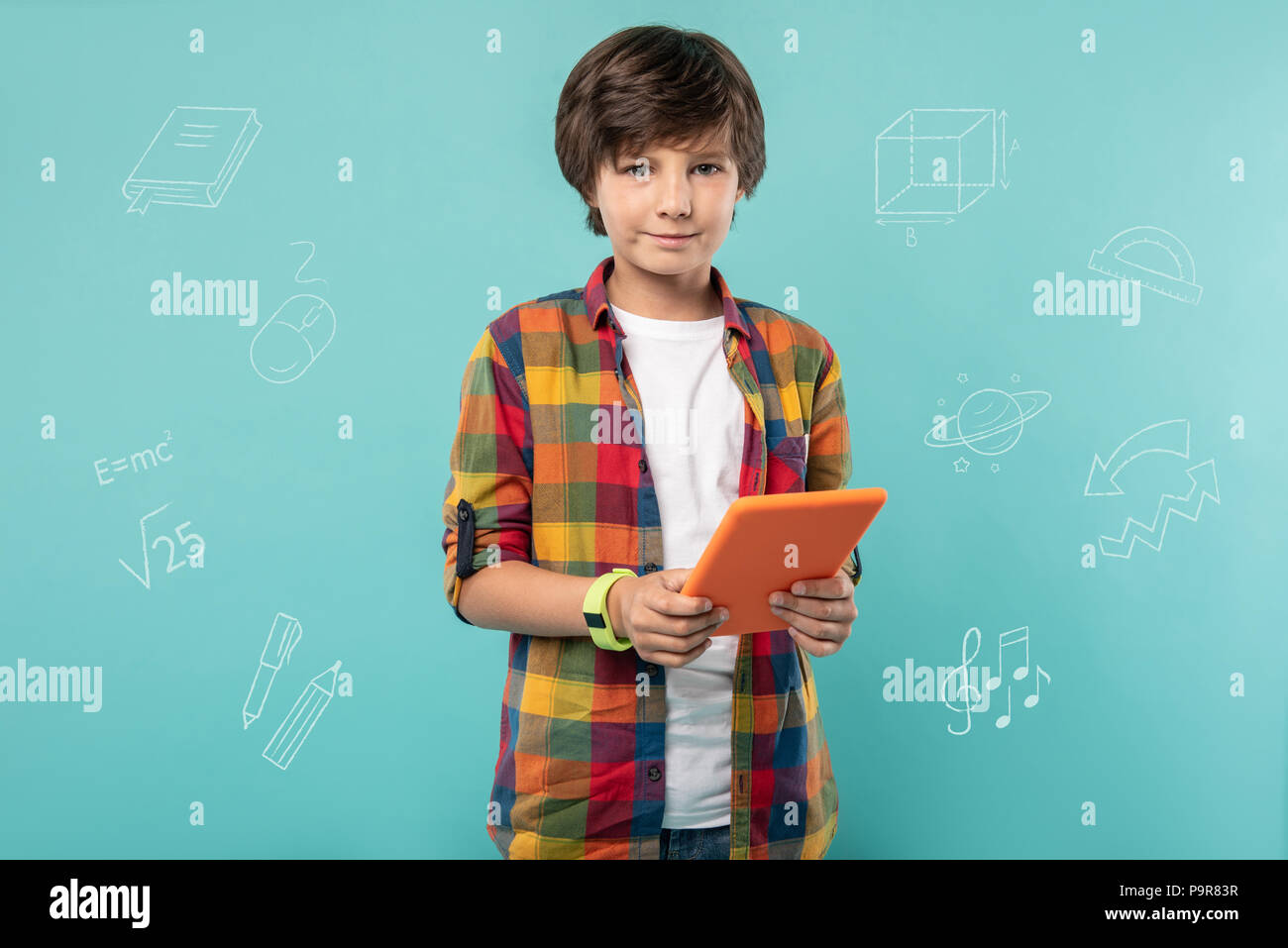Calm boy feeling confident while standing with a tablet Stock Photo - Alamy