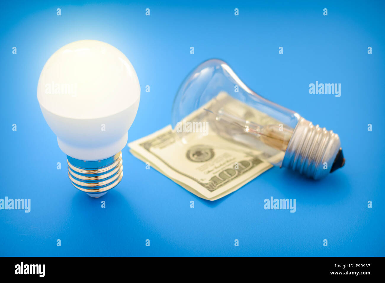 Led light bulb lay next to incandescent bulb and dollar bill. Concept ...