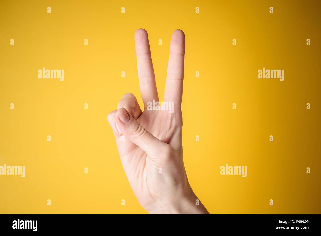 woman hand victory sign gesture isolated on yellow background Stock ...