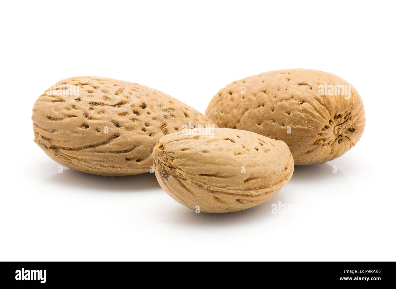 Three unshelled almonds isolated on white background Stock Photo - Alamy