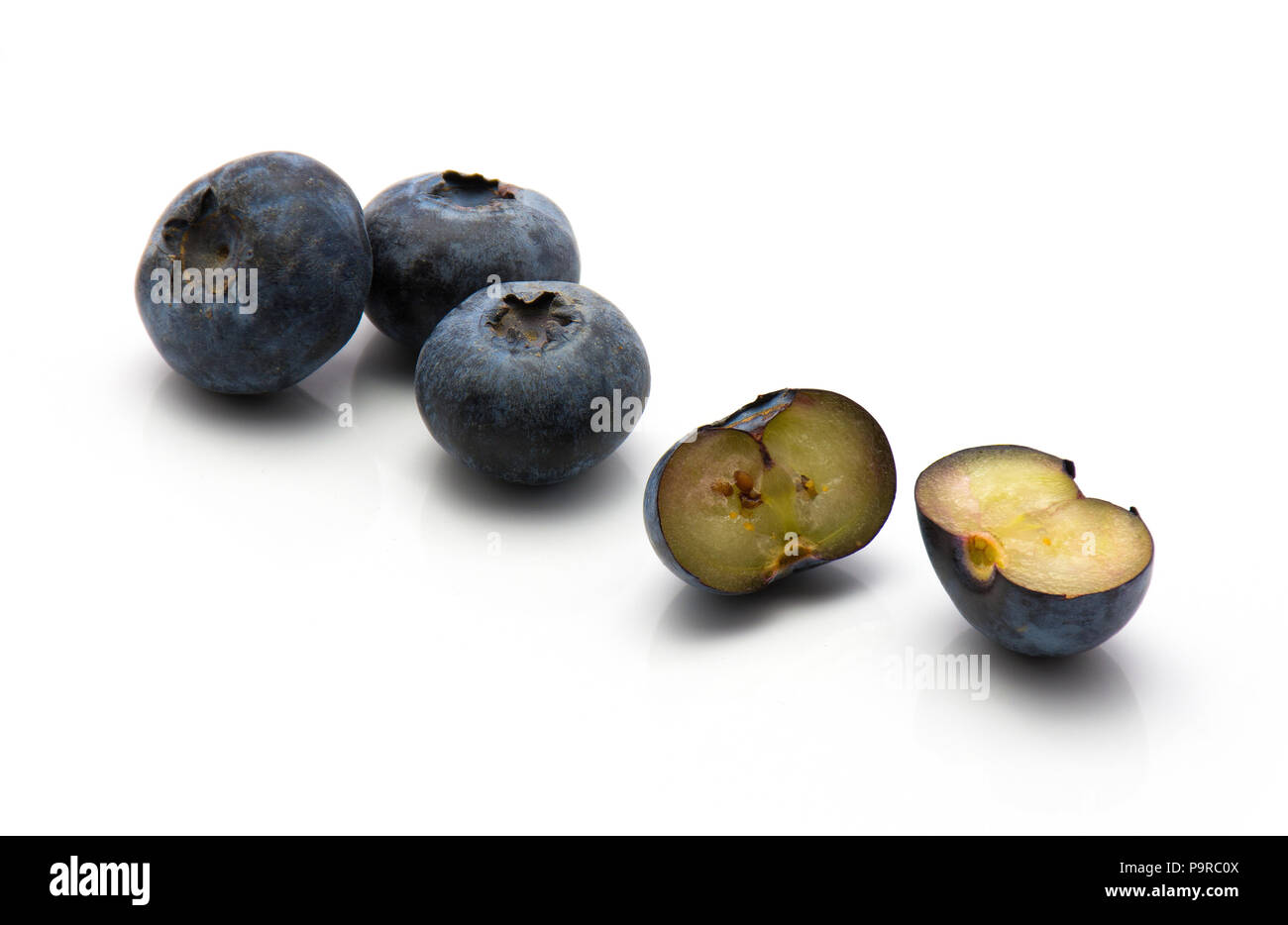 Bog blueberries isolated on white background three whole and one cut in ...