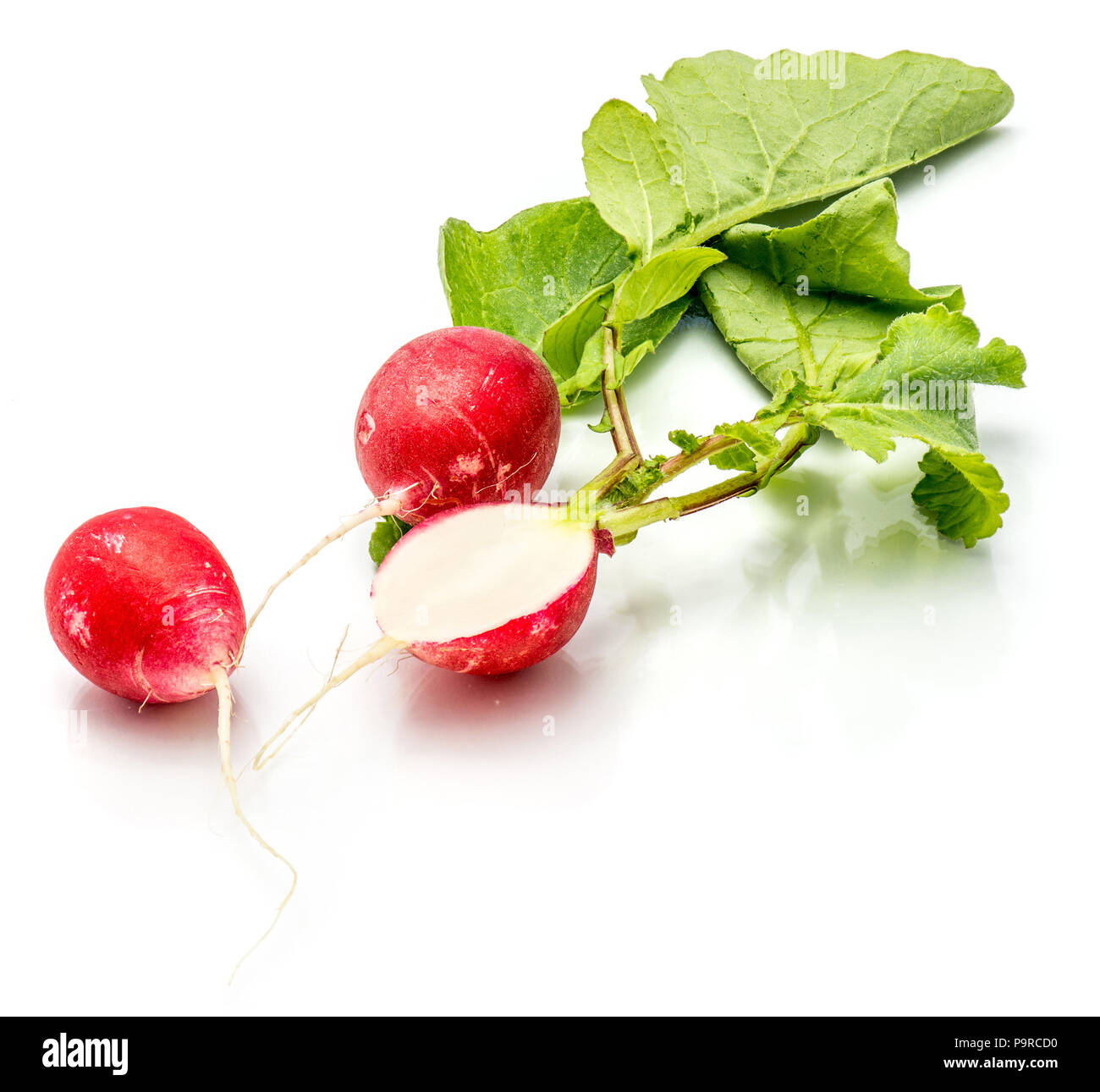 Two whole and sliced red radish, one half, fresh green leaves, isolated ...