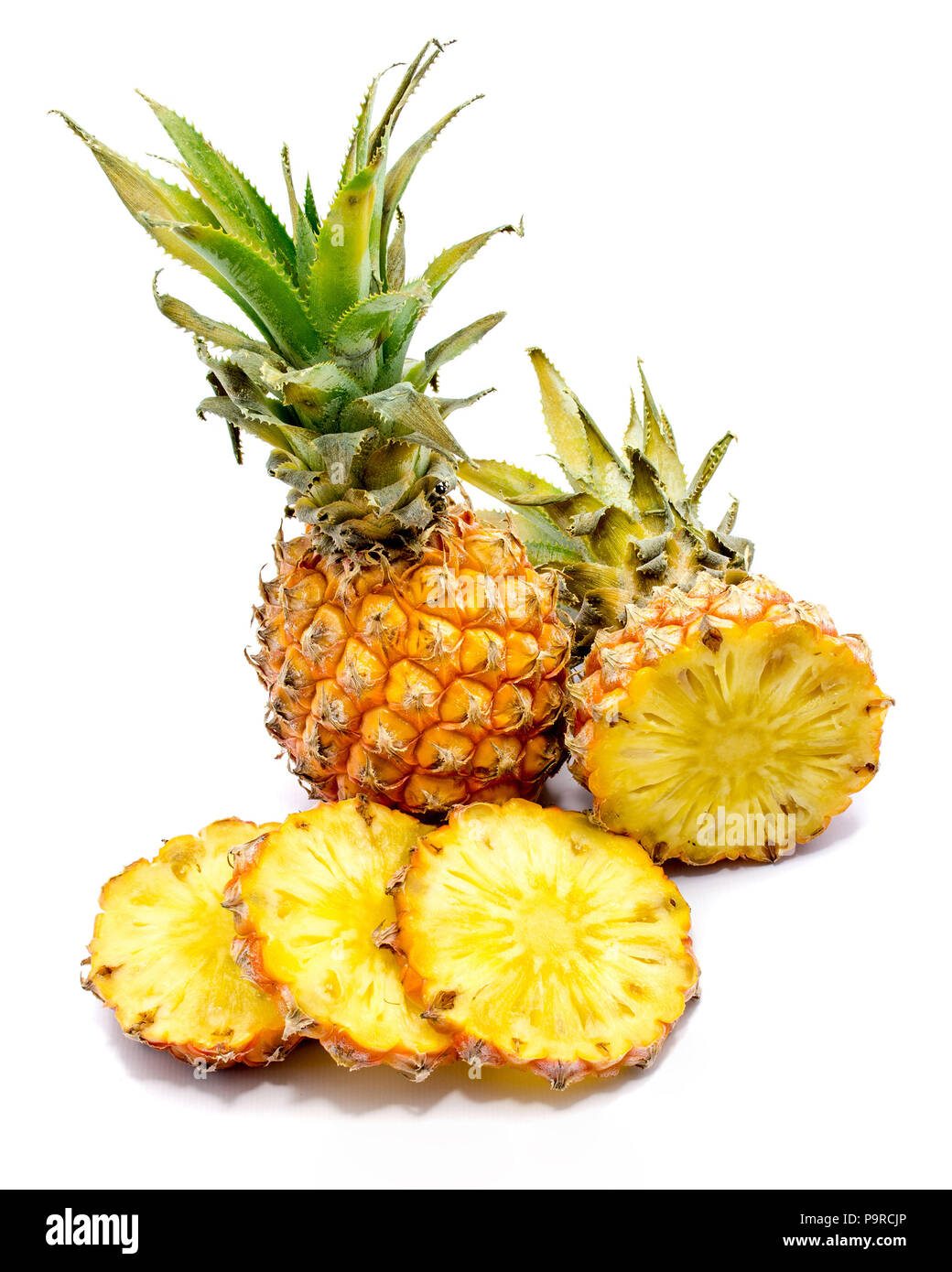 Fresh round pineapple slices and one whole pineapple with green leaves ...