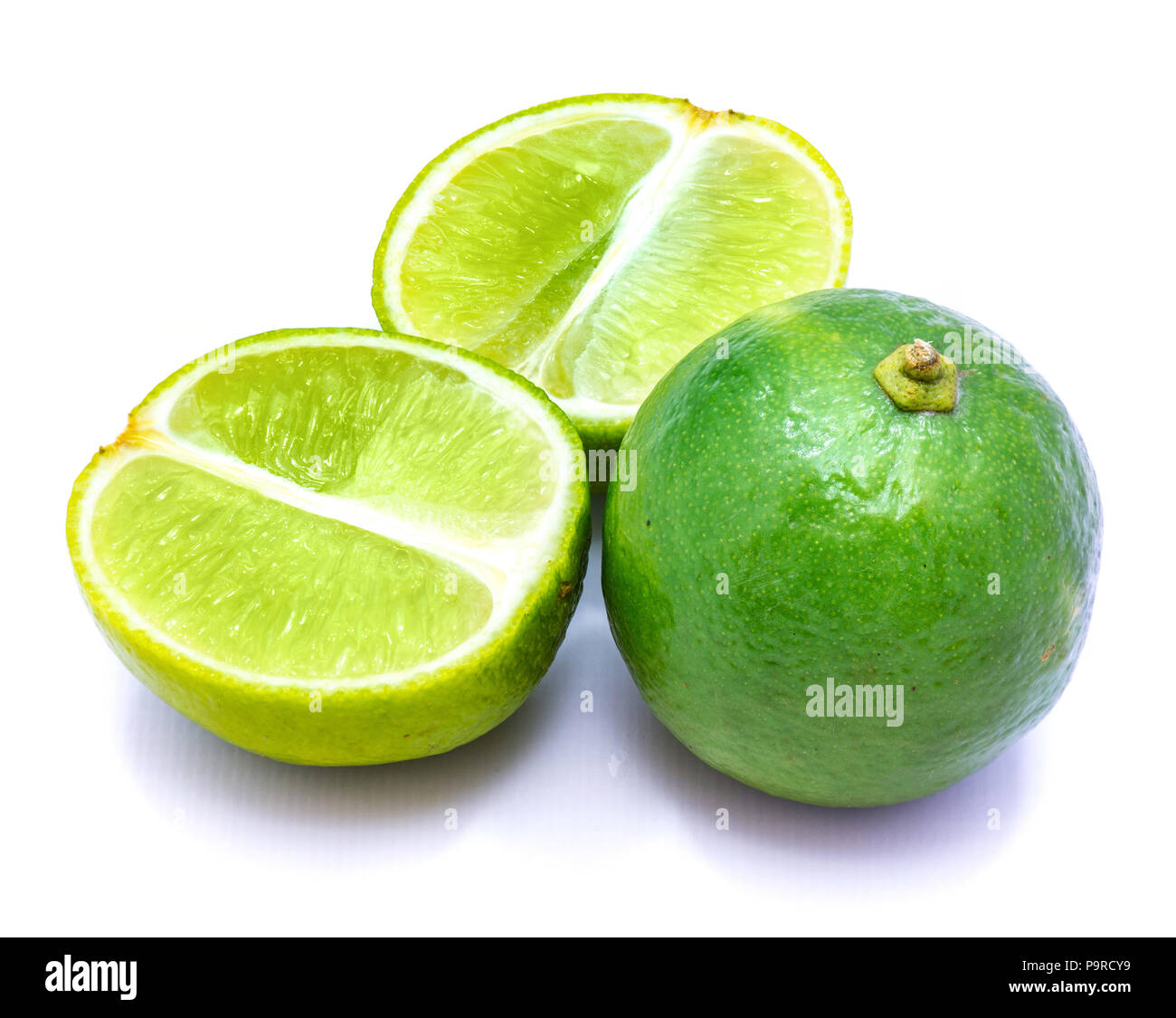 One whole and two lime halves isolated on white studio background Stock ...