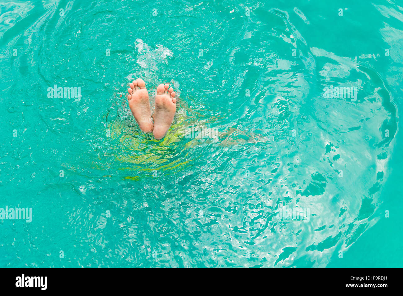 Top view of a man diving into water in a swimming pool with feet up ...