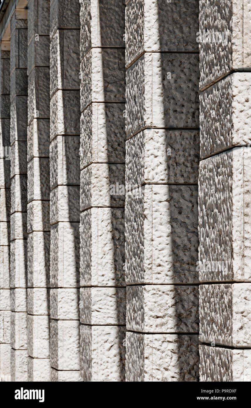 Building section ,a long row of squared columns lighted by the sun ...
