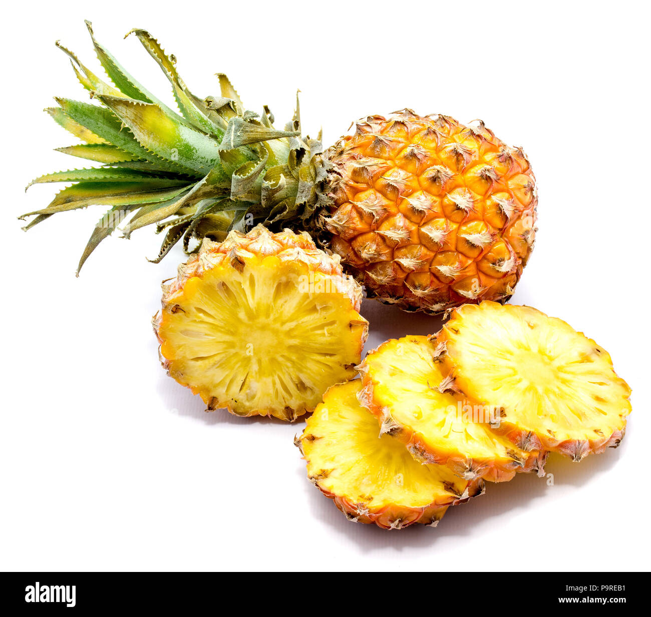 Fresh round pineapple slices and one whole pineapple with green leaves ...