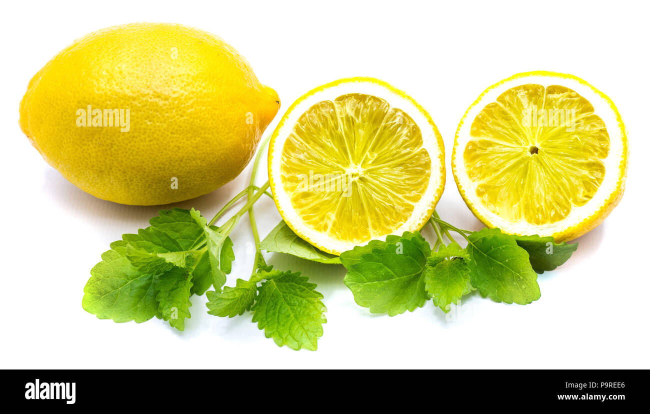 One whole yellow two halves and fresh green lemon balm leaves isolated ...