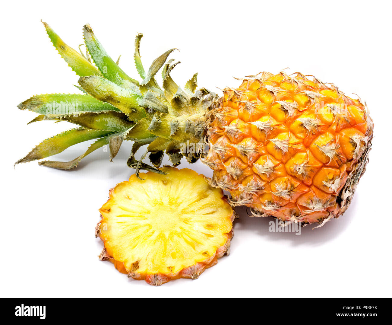 Fresh round pineapple slice and one whole pineapple with green leaves ...