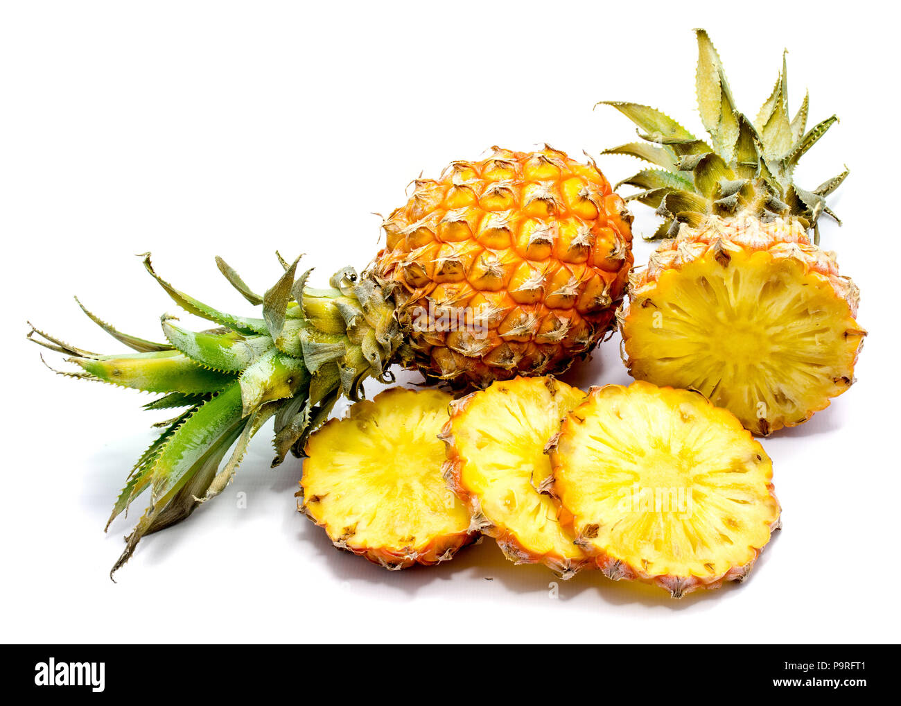 Fresh round pineapple slices and one whole pineapple with green leaves ...
