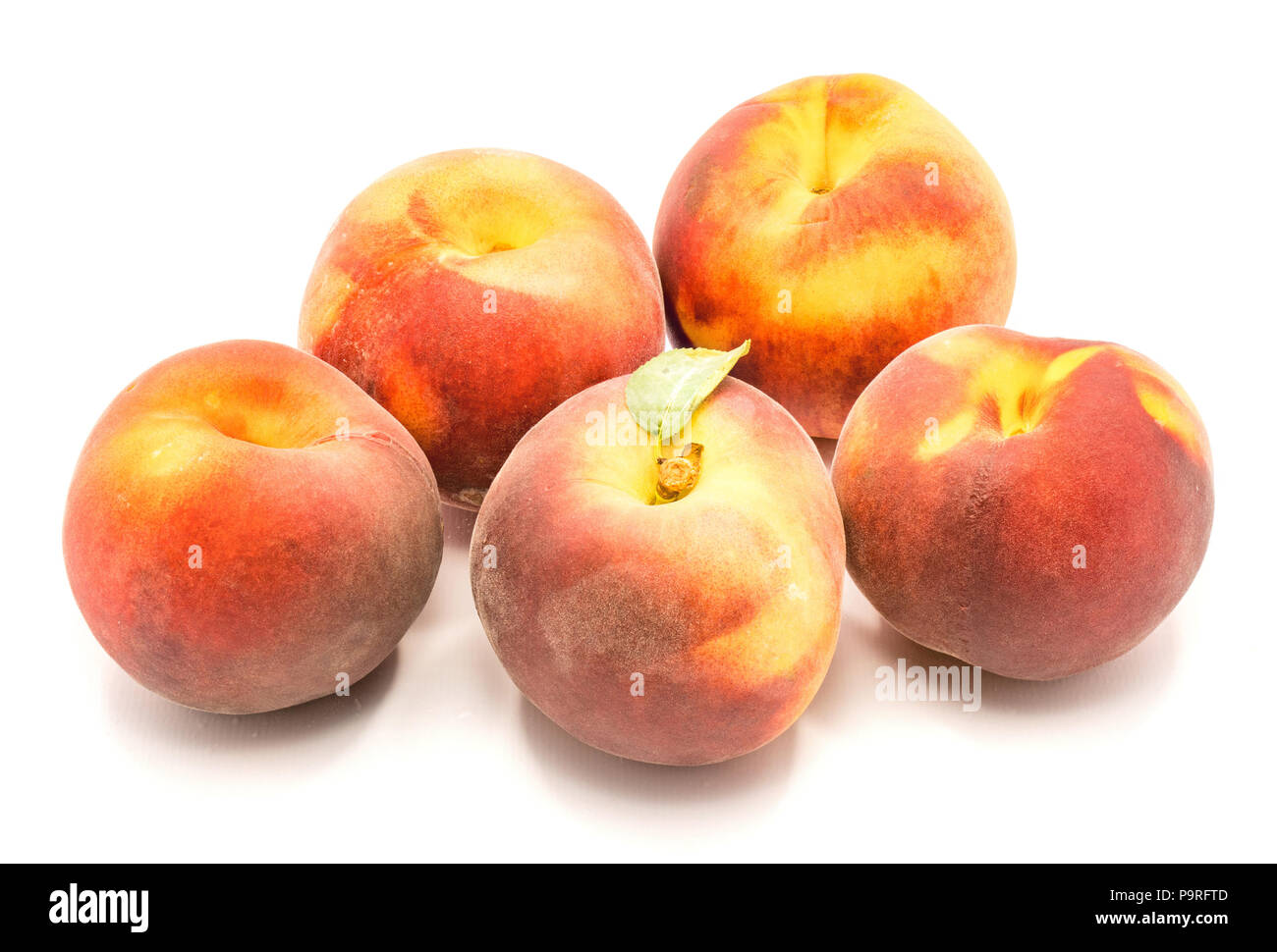 Group of five whole peaches, one with green leaf, isolated on white ...