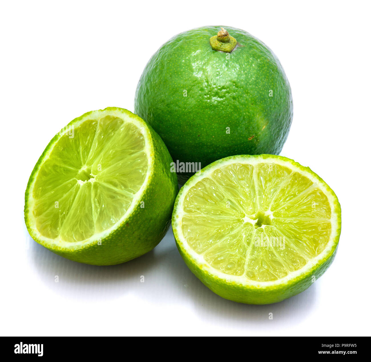 One whole lime and two cross section halves isolated on white ...