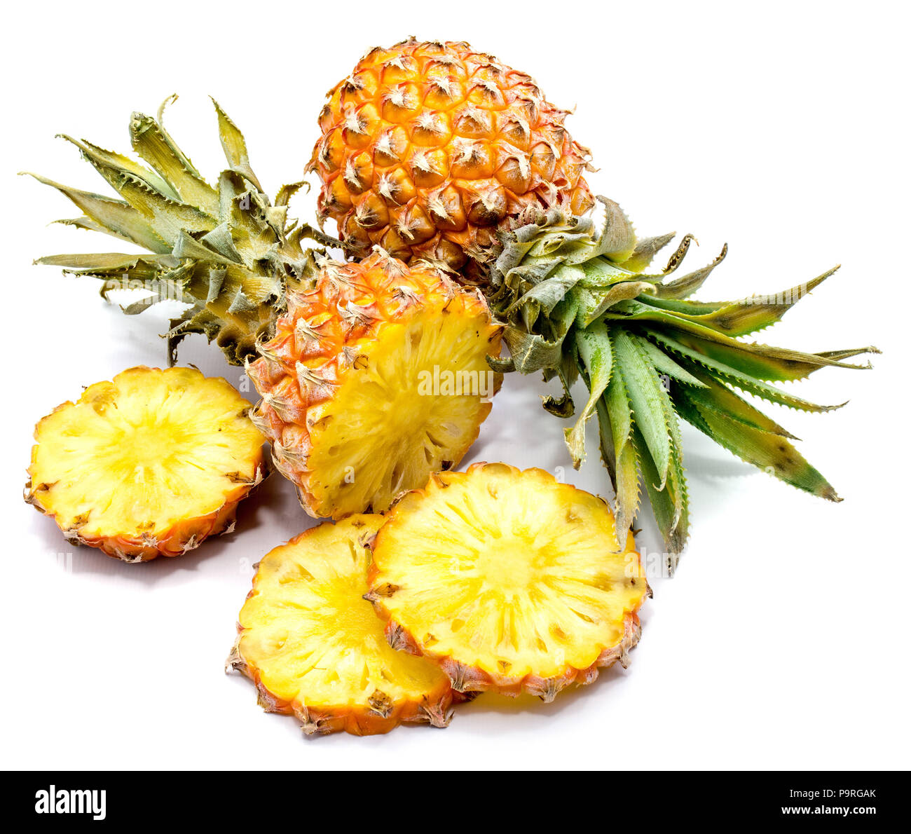 Fresh round pineapple slices and one whole pineapple with green leaves ...
