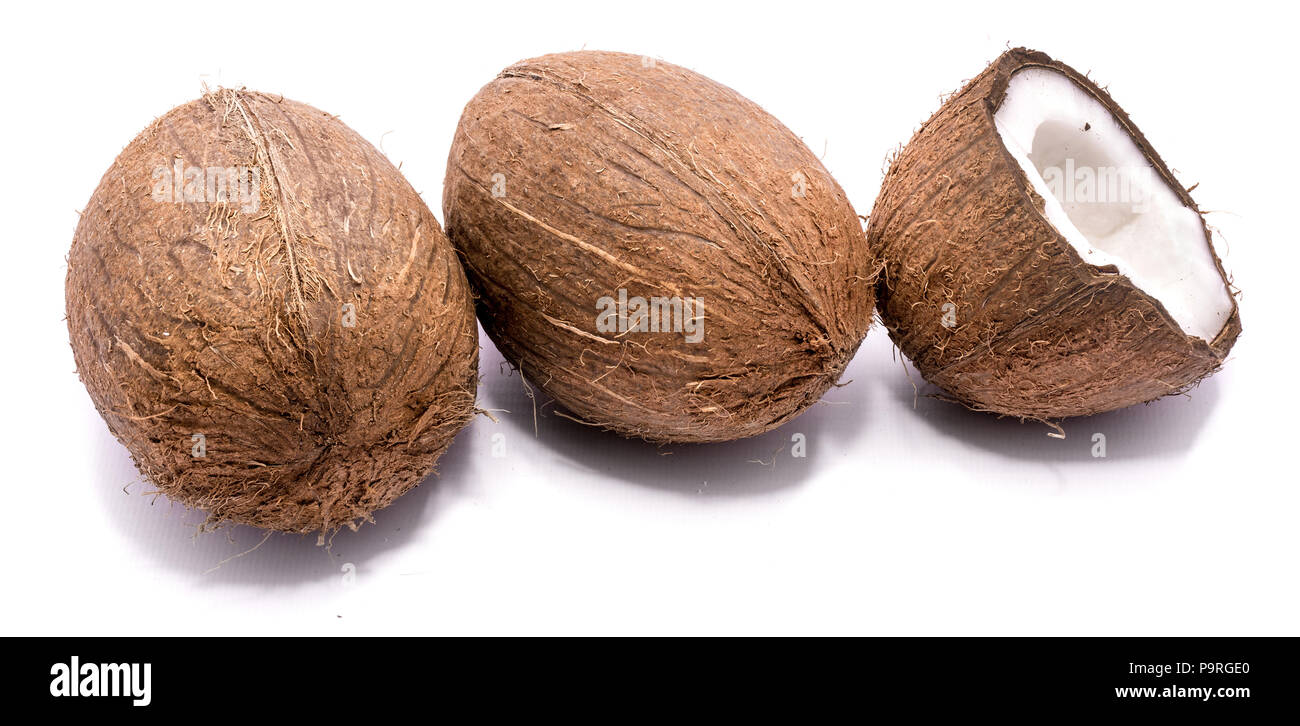 Two whole coconuts and one cracked coconut half isolated on white ...