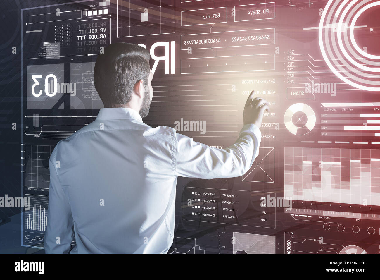 Touching futuristic screen. Busy young computer programmer touching the transparent screen while ...