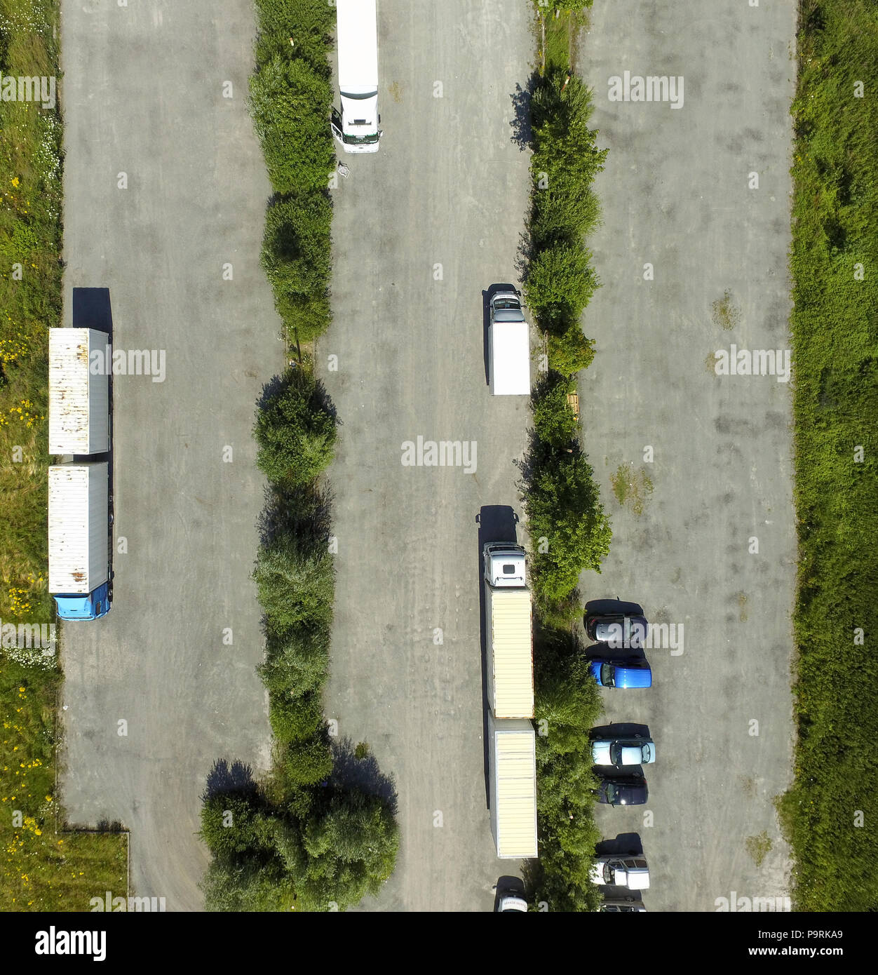 Vertical aerial view of an almost empty asphalted grey parking lot with ...