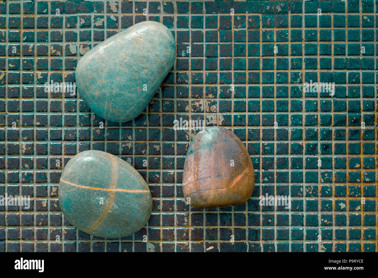 three stones on a gridded metal surface. Copy space Stock Photo - Alamy