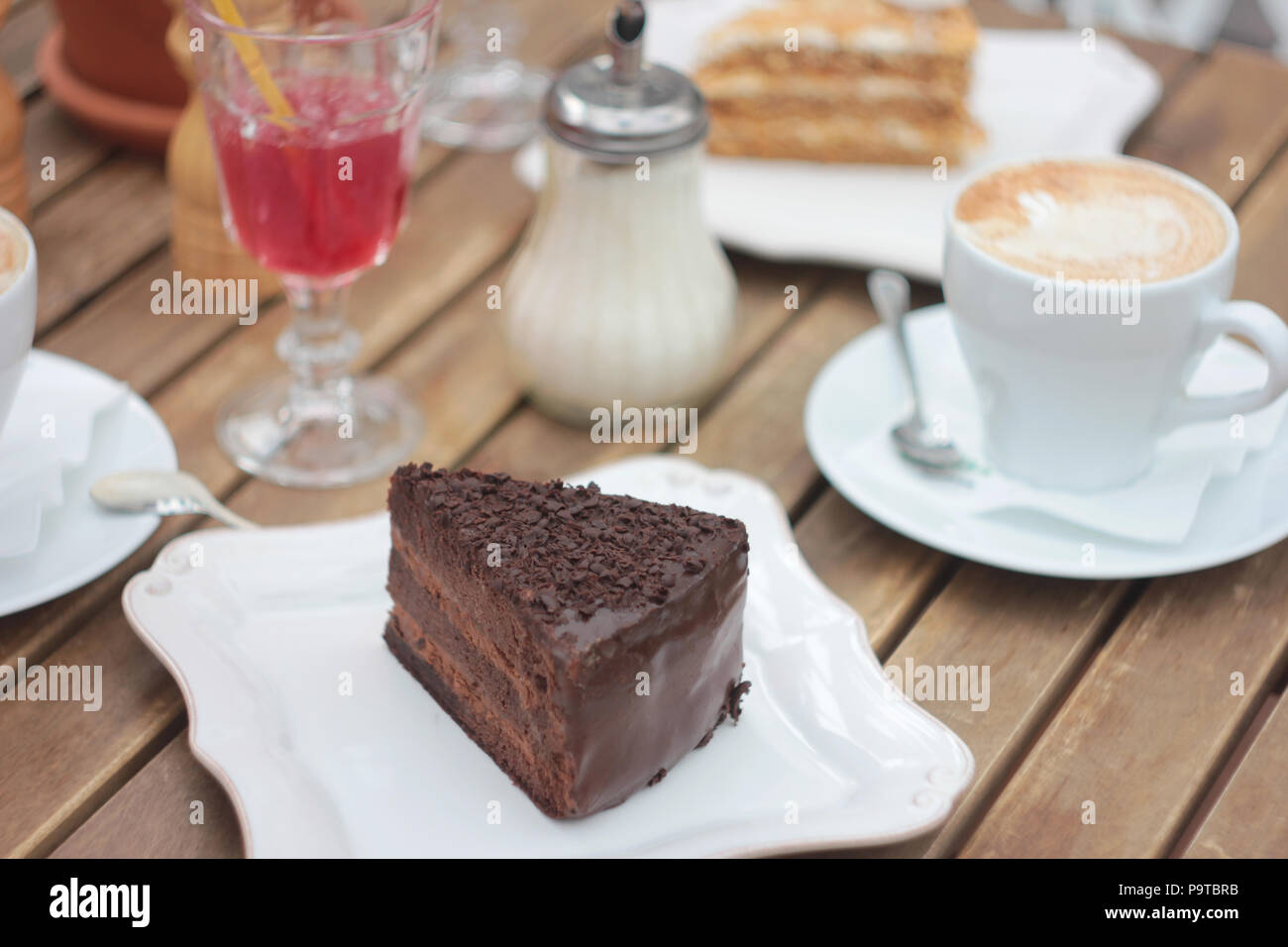 The piece of chocolate cake on table of summer terrace in cafe, picnic ...
