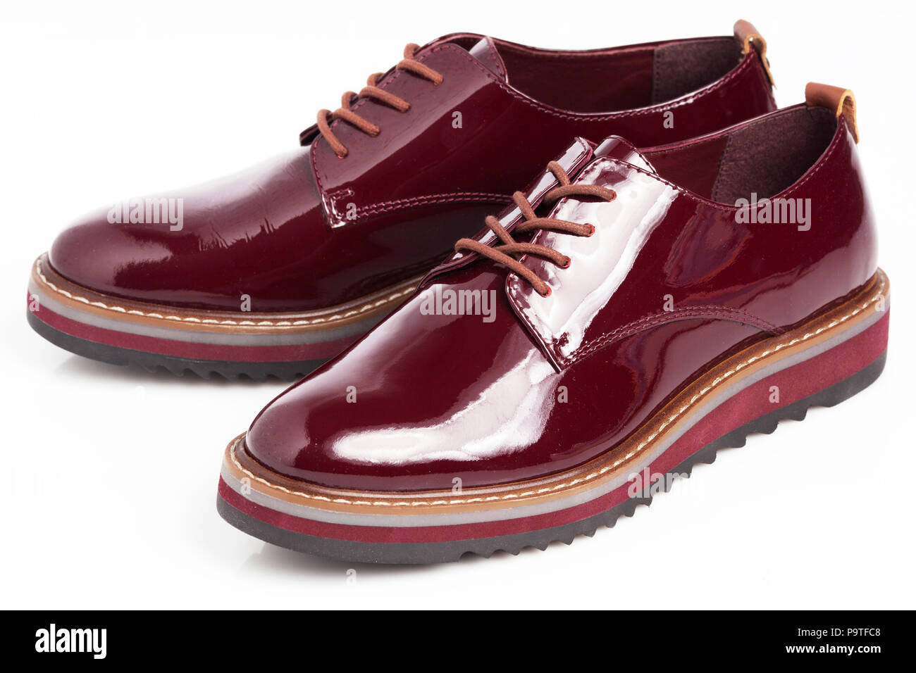 Deep red shiny pair of shoes on a white background Stock Photo - Alamy